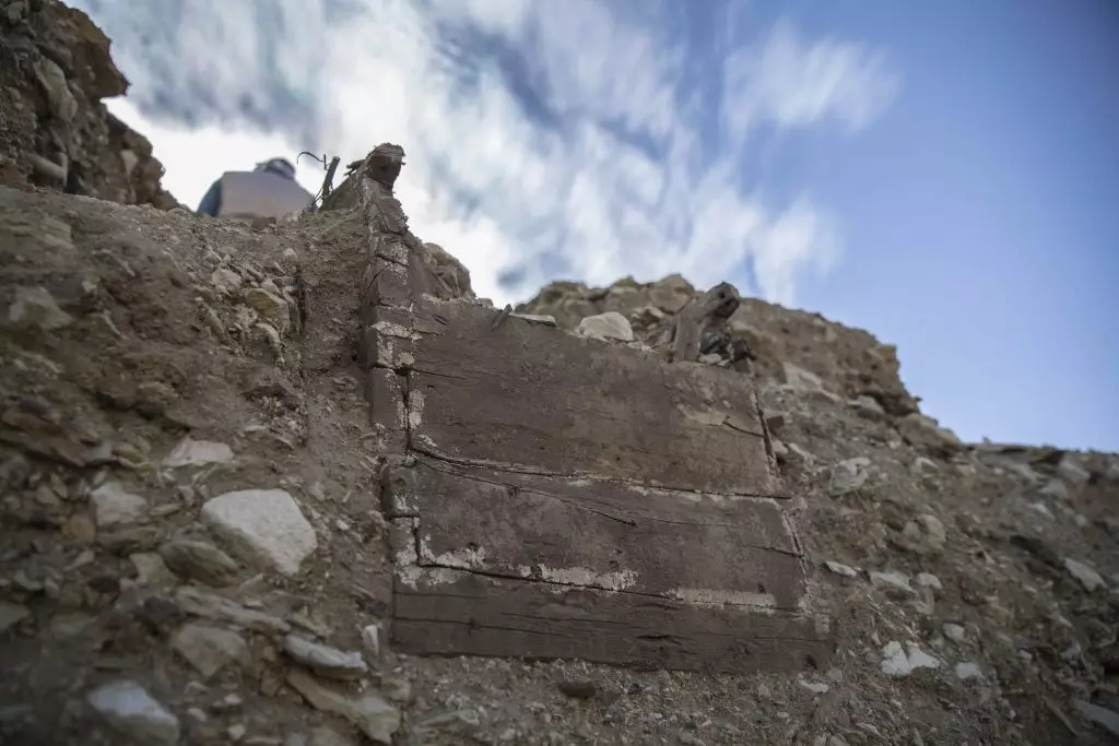 Baƙi suna wucewa ta wani sarcophagus na katako wanda har yanzu yake binne. (Hoto daga KHALED DESOUKI/AFP ta hanyar Getty Images)