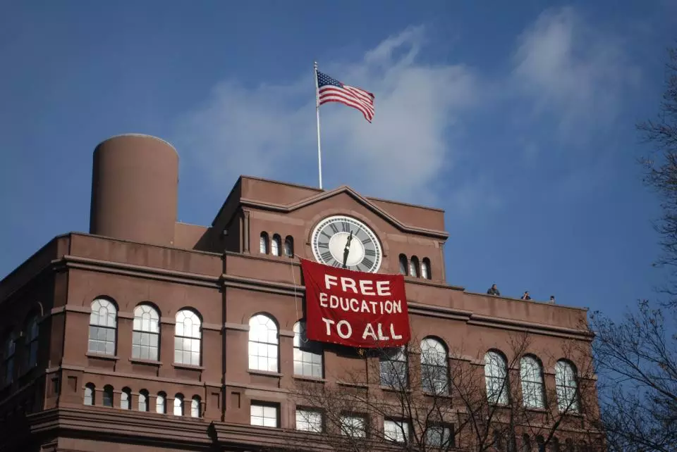 Studerende hænger banner under det historiske klokketårn ved Cooper Union i New York City under en besættelse i 2012, hvor de protesterede mod implementering af undervisning i den historisk friskole. Foto af Free Cooper Union, Creative Commons Navngivelse-Del ens 3.0 Unported-licens.