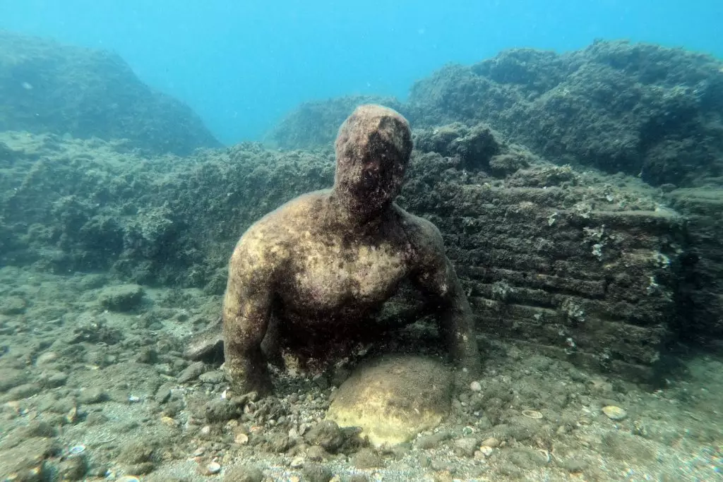 Uma cópia de uma estátua original, conservada no Museu de Baiae, de Baios oferecendo uma taça de vinho a Polifemo, no Nymphaeum de punta Epitaffio, na antiga cidade romana submersa de Baia no Parque Arqueológico Subaquático de Baia, parte do Complexo do Parque Arqueológico Campi Flegrei em Pozzuoli, perto de Nápoles. Foto de Andreas Solaro/AFP via Getty Images.