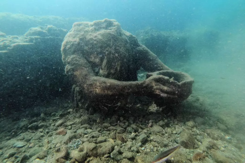 Uma cópia de uma estátua original, conservada no Museu de Baiae, de Baios oferecendo uma taça de vinho a Polifemo, no Nymphaeum de punta Epitaffio, na antiga cidade romana submersa de Baia no Parque Arqueológico Subaquático de Baia, parte do Complexo do Parque Arqueológico Campi Flegrei em Pozzuoli, perto de Nápoles. Foto de Andreas Solaro/AFP via Getty Images.