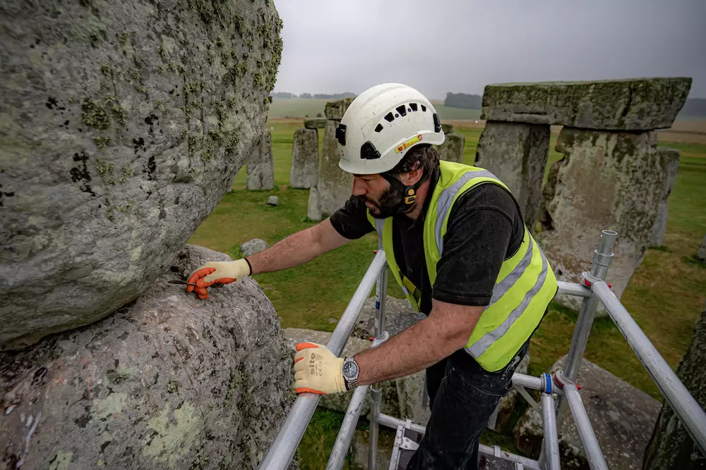 Gumagamit ang Conservator na si James Preston ng pointing spoon sa ibabaw ng plantsa na itinayo sa loob ng bilog na bato sa Stonehenge bilang mga espesyalistang kontratista mula sa mga depekto sa pagkumpuni ng SSH Conservation mula sa mga nakaraang pagkukumpuni, na isinagawa noong 1950's, sa isang trilithon sa bilog na bato at nagsasagawa ng mahahalagang gawaing konserbasyon sa Stonehenge, Wiltshire . Petsa ng larawan: Martes Setyembre 14, 2021. (Larawan ni Ben Birchall/PA Images sa pamamagitan ng Getty Images)