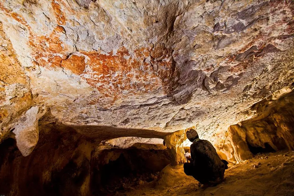 Un investigador que estuda a que antes se cría que era a arte figurativa máis antiga do mundo nunha cova de Borneo. O achado foi suplantado por un novo descubrimento en Indonesia. Foto de Pindi Setiawan.