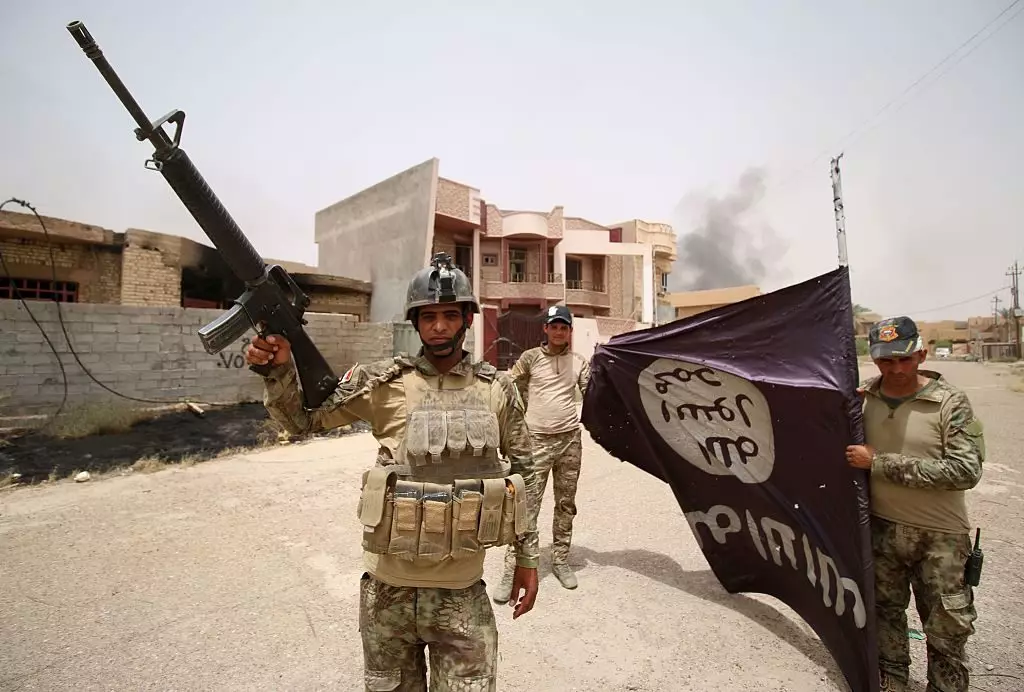 Dakarun da ke goyon bayan gwamnatin Iraki rike da tutar kungiyar IS a Falluja a lokacin da suke kokarin kawar da mayakan IS a ranar 19 ga watan Yuni, 2016. Hoton Haidar Mohammmed Ali/AFP/Getty Images.