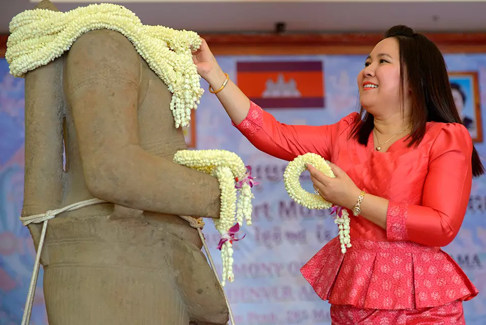 Haweeney Cambodia ah ayaa dhigata ubax ku wareegsan farshaxan-sanadeedka ilaaha Hinduuga ee Rama ee qarnigii 10-aad ka dib markii laga soo celiyay Matxafka farshaxanka Denver ee Mareykanka intii lagu jiray xaflad ka dhacday Golaha Wasiirada ee Phnom Penh Maarso 28, 2016. The 62- Torso-dherer inch ah, oo laga xaday 1970-nadii laga soo xaday macbadka Koh Ker ee u dhow dhismaha caanka ah ee Angkor Wat, ayaa waxaa wareejiyay madxafka, kaasoo haystay tan iyo 1986. Sawirka: Tang Chhin Sothy/AFP/Getty Images.