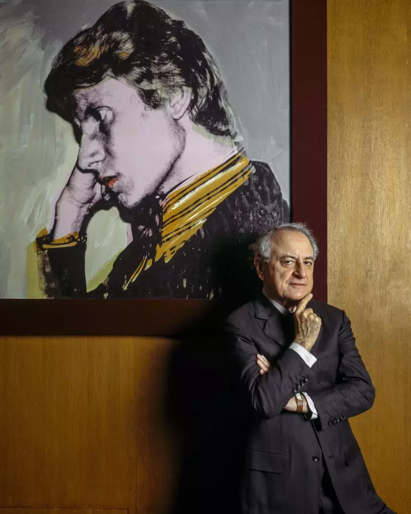 Pierre Bergé em seu escritório em 1999 com um retrato de Andy Warhol de Yves Saint Laurent. Foto cortesia da Sotheby's Paris, ©Derek Hudson/Getty Images/Andy Warhol Foundation for the Visual Arts, Inc.