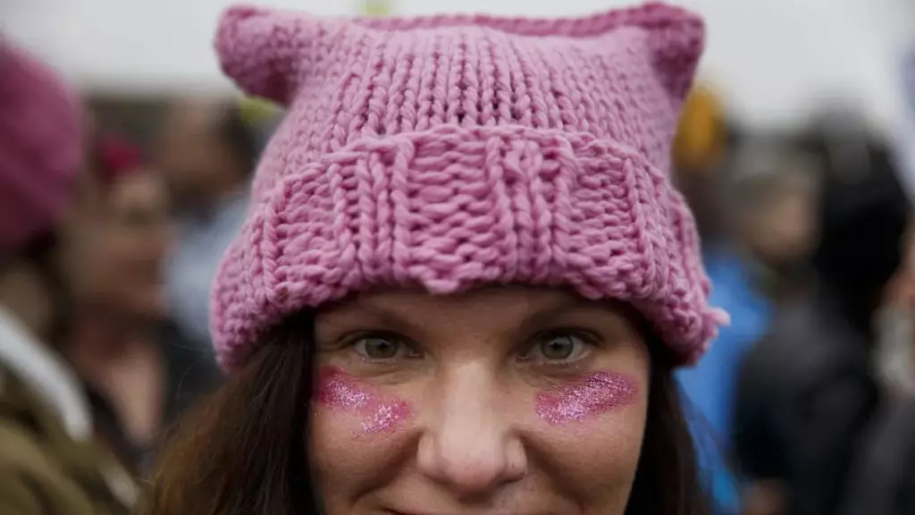 En demonstrant står för ett fotografi medan han bär en rosa hatt under Women's March på Washington i Washington, DC, lördagen den 21 januari 2017. Foto av Patrick T. Fallon/Bloomberg via Getty Images.