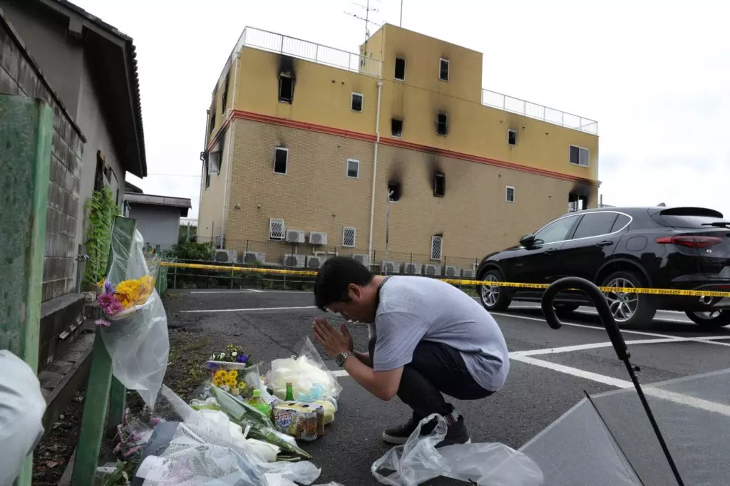 Een man bidt naast eerbetoon aan slachtoffers van de aanslag op Kyoto Animation, 19 juli. Foto door Buddhika Weerasinghe AFP/Getty Images.