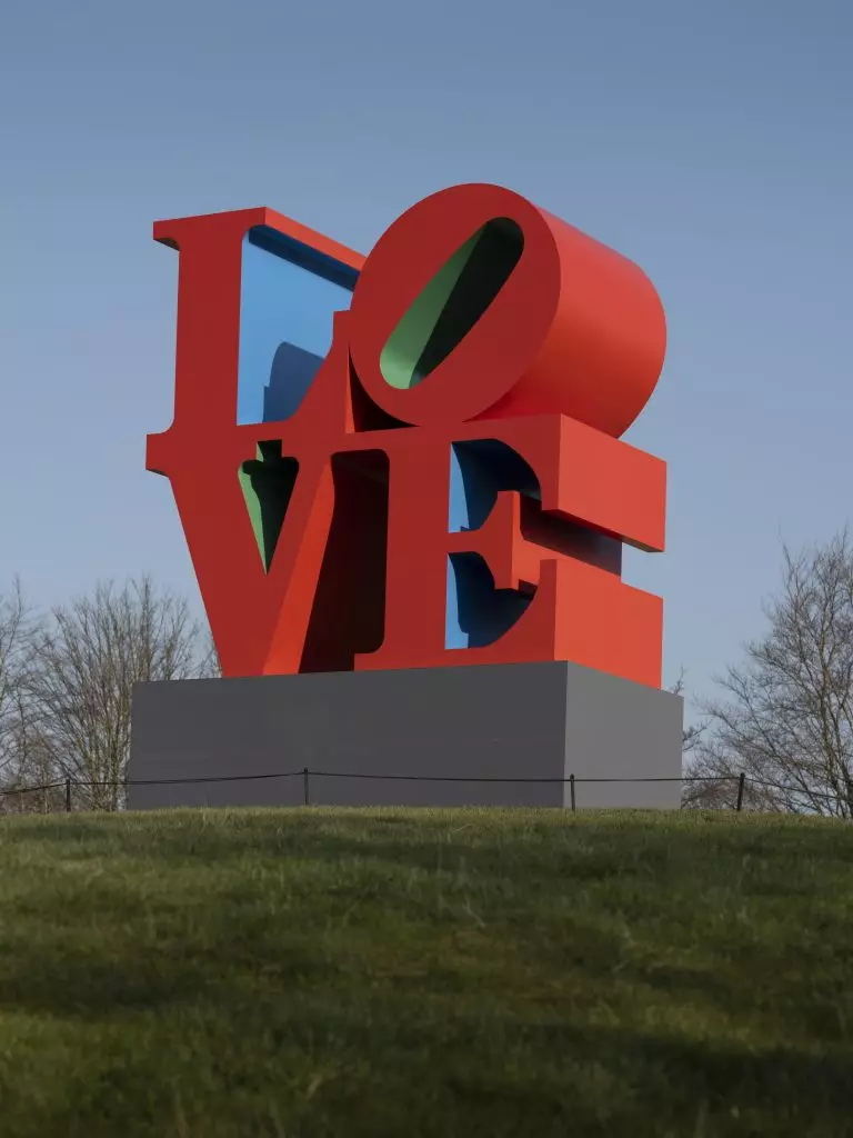 Robert Indiana, LOVE (Red Blue Green) (1966-1998). Radharc suiteála ag Páirc Dealbhóireachta Yorkshire, 2022. Grianghraf: © Jonty Wilde, le caoinchead Pháirc Dealbhóireachta Yorkshire. Saothar Ealaíne: © 2022 Morgan Art Foundation Ltd./ Artists Rights Society (ARS), Nua Eabhrac/DACS, Londain