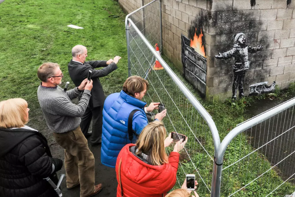 Batho ba bokana ho pota-pota terata e hahiloeng ho sireletsa karolo ea morao-rao ea bonono ea Banksy e Port Talbot, Wales. Senepe ka Matt Cardy/Getty Images.