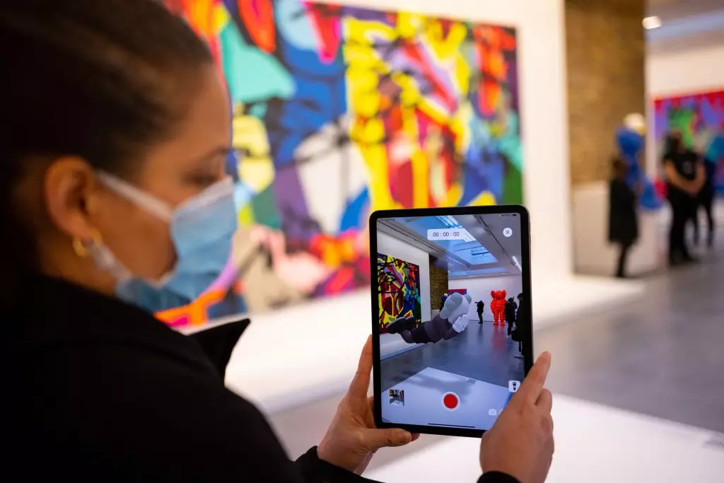 In personielslid brûkt de Acute Art-app om in (AR) augmented reality-keunstwurk mei de titel COMPANION (EXPANDED) fan 'e Amerikaanske keunstner KAWS te werjaan, tidens in parsefoarbyld foar de tentoanstelling 'KAWS: NEW FICTION' yn 'e Serpentine North-galery yn Londen op 18 jannewaris 2022. - BEPERK TOT REDAKKSJE GEBRUK - Ferplichte fermelding fan 'e keunstner BY PUBLICASJON - OM HET EVENT TE ILLUSTRATERE SOM SPESIFISEERD YN DE BYSKRIFT (Foto troch Tolga Akmen / AFP) / BEPERK TOT REDAKTIONELE GEBRUK FAN REDAKSJONEEL GEBRUIK - PUBLICATIE FAN KUNSTGEBRUK OM HET EVENT TE ILLUSTRATERE SOM SPESIFISEERD YN DE BETJEKJE / BEPERKTE TOT REDAKANT GEBRUIK - Ferplichte fermelding fan 'e artyst BY PUBLIKASJON - OM HET EVENT TE ILLUSTRATERE SAS SPESIFISEERD IN DE BYSKRIFT (Foto troch TOLGA AKMEN/AFP fia Getty Images)