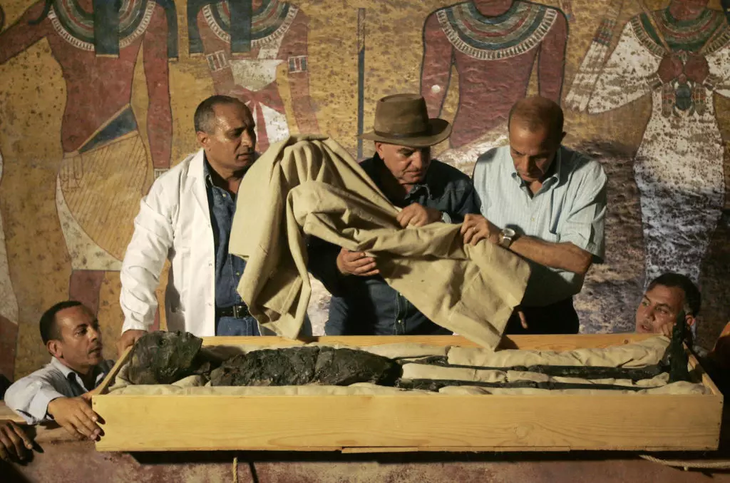 Ägypten Antiquitéite Chef Zahi Hawass iwwerwaacht d'Ewechhuele vun der Linnen-wéckelt Mumie vum Kinnek Tutankhamun vu sengem Steen Sarkophag a sengem ënnerierdesche Graf am berühmten Dall vun de Kinneken zu Luxor, 04. November 2007. Foto Ugedriwwe vum Ben Curtis / AFP / Getty Images.