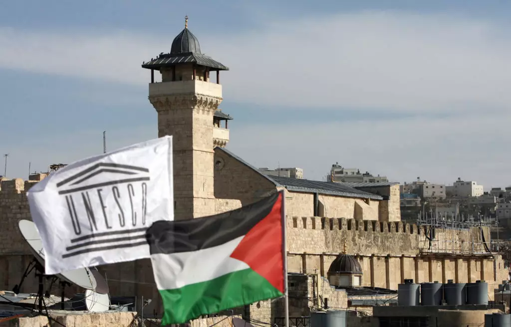 Ang Palestinian Rehabilitation Committee nagpataas sa bandera sa UNESCO sunod sa nasudnong Palestinian nga bandila atubangan sa Hebron's Ibrahimi Mosque o sa Tomb of the Patriarchs niadtong 2011, usa ka bulan human sa pagsulod sa mga Palestinian sa UN cultural agency nakapukaw sa kasuko ug pagbalos gikan sa Estados Unidos ug Israel. Hazem Bader/AFP/Getty Images.