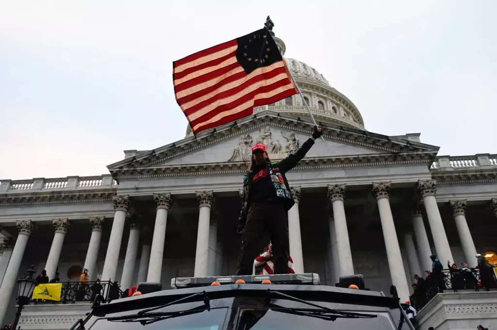 Mfuasi wa Trump anapeperusha bendera anaposimama kwenye gari la serikali mbele ya Ikulu ya Marekani mnamo Januari 6, 2021. (Picha na Andrew Caballero-Reynolds/AFP/Getty Images.