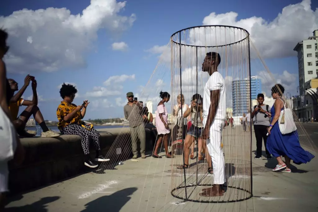 Atis Kiben-Ameriken Carlos Martiel kanpe andedan pwojè atizay li a, The Blood of Cain, sou bòdmè Malecon la pandan 13yèm fwa atis la Havana Biennial, 14 avril 2019 nan Lahavàn, Kiba. Foto: Sven Creutzmann / Mambo foto / Geti Images.