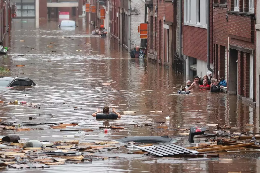 Mae dynes yn rhydio i lawr stryd dan ddŵr yn dilyn glaw trwm yn Liege, ar 15 Gorffennaf, 2021. Llun: Bruno Fahy/Belga/AFP. Gwlad Belg ALLAN trwy Getty Images.