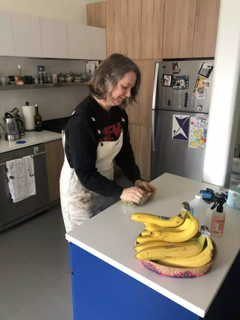 Gina Beavers v kuchyni, otevírá salát Trader Joe. Foto s laskavým svolením umělce.