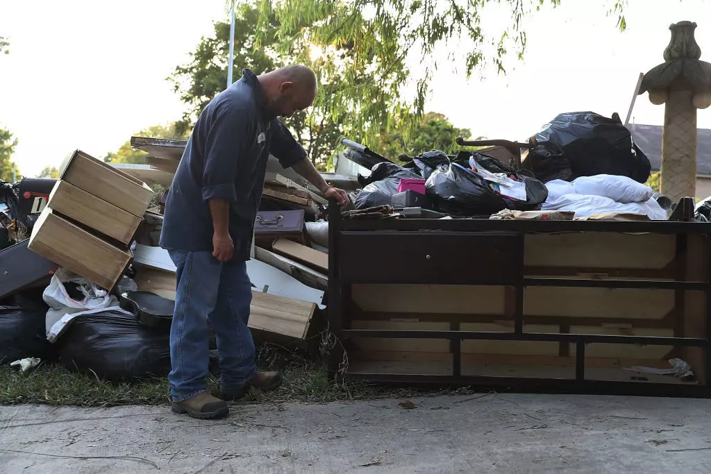 ארנסטו רמירז עוצר כשהוא מנקה את ביתו שהוצף במים לאחר שגשמים עזים גרמו להצפות נרחבות במהלך ההוריקן והסופה הטרופית הארווי ב-2 בספטמבר 2017 ביוסטון, טקסס. תמונה מאת ג'ו ריידל/Getty Images.