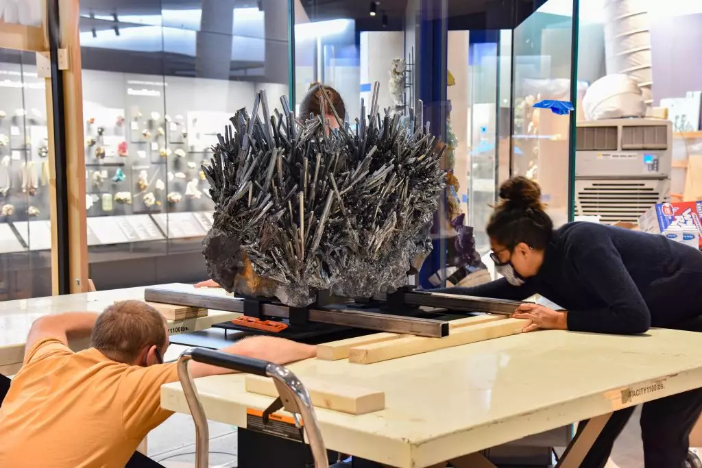 Os membros do persoal da exposición instalan un espécime de estibinita de case media tonelada nas novas Salas de Xemas e Minerais do Museo Americano de Historia Natural. Foto de D. Finnin, ©Museo Americano de Historia Natural.