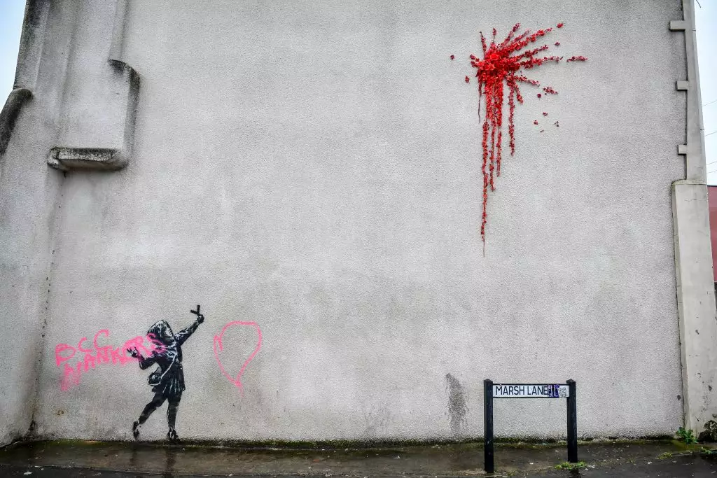 ວຽກງານສິລະປະຂອງ Banksy ຢູ່ຂ້າງເຮືອນຫຼັງໜຶ່ງໃນ Marsh Lane, Barton Hill, Bristol, ໄດ້ຖືກທຳລາຍດ້ວຍສີສີພົ່ນສີຊົມພູ ໃນມື້ທີ່ມັນໄດ້ຖືກເປີດເຜີຍໃນວັນແຫ່ງຄວາມຮັກ. ຮູບພາບໂດຍ Ben Birchall/PA Images ຜ່ານ Getty Images.