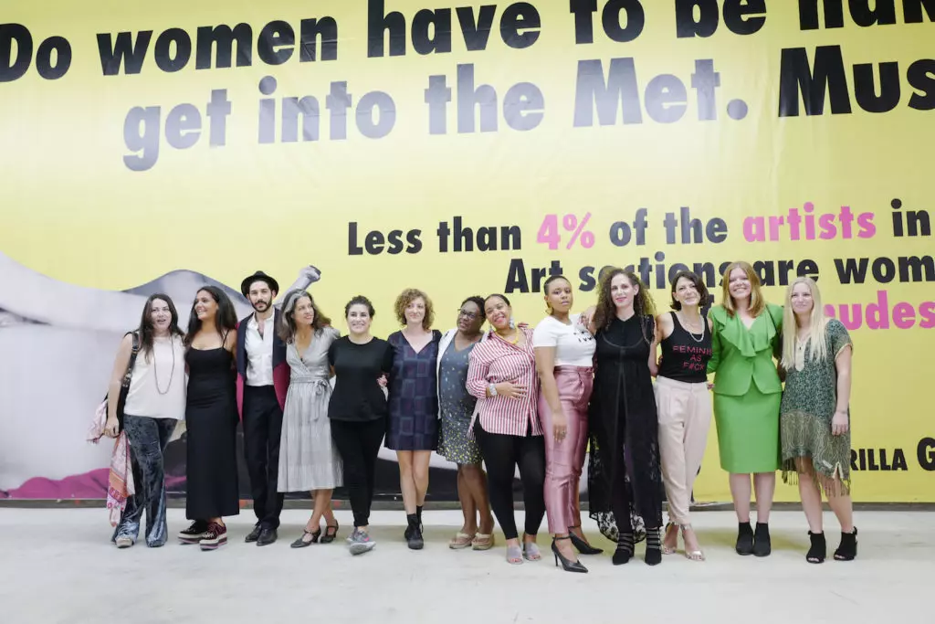 Les organisateurs Zoe Lukov et Anthony Spinelli avec des invités à Fair., l'exposition d'art féminin, devant une œuvre des Guerrilla Girls. Photo publiée avec l'aimable autorisation de BFA.