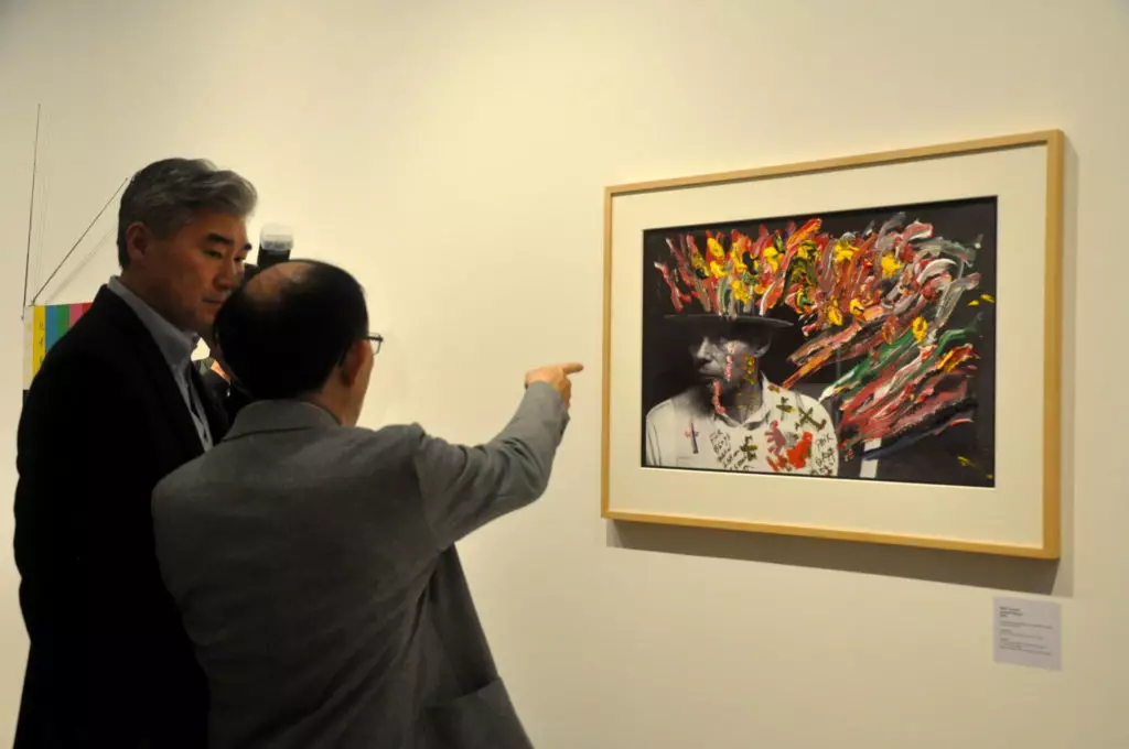 Ambasadorul SUA în Filipine, S.E. Sung Kim [stânga], discutând despre un portret mixt media Nam June Paik al lui Joseph Beuys cu domnul Ken Hakuta (dreapta), prin amabilitatea León Gallery International.