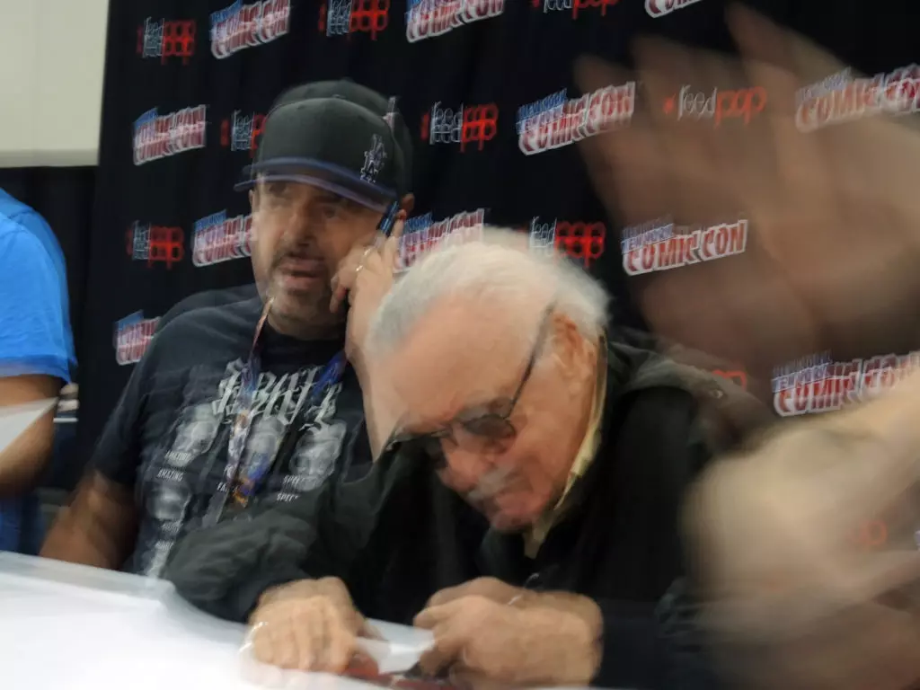 Stan Lee ເຊັນລາຍເຊັນໃນງານ New York Comic Con 2016 ໃນຂະນະທີ່ຜູ້ຈັດການຂອງລາວພະຍາຍາມປ້ອງກັນຈາກການຖ່າຍຮູບຂອງນິທານກາຕູນ. ມາລະຍາດຈາກ Sarah Cascone.