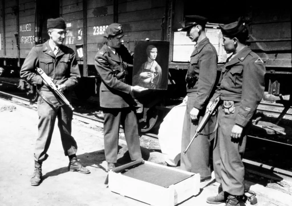 Faamanatu Men Lt. Frank P. Albright, Polish Liaison Officer Mej. Karol Estreicher, Monuments Man Capt. Everett Parker Lesley, ma Pfc. Joe D. Espinosa, leoleo ma le 34th Field Artillery Battalion, pose ma Leonard da Vinci's Lady ma le Ermineu ina ua toe foi atu i Polani ia Aperila 1946.