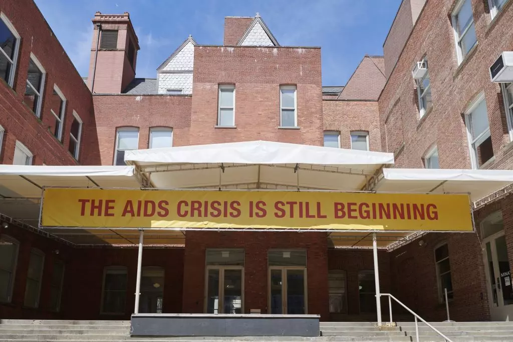 O banner que leva ao MoMA PS1. Cerca de 36 milhões de pessoas em todo o mundo têm o vírus HIV. Apenas cerca de metade deles tem acesso a medicamentos que salvam vidas. Gregg Bordowitz, A crise da AIDS ainda está começando (2021). Imagem cortesia do MoMA PS1. Foto: Kyle Knodell.