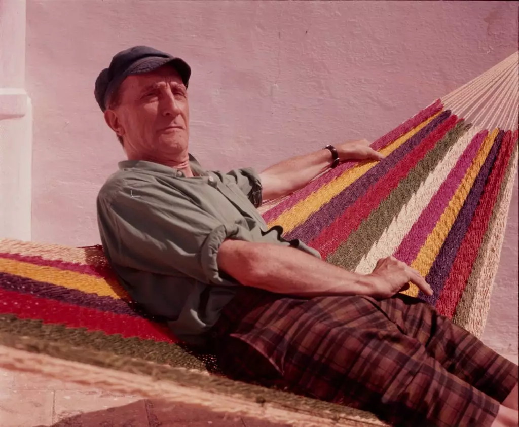 Pictiúr le Man Ray de Marcel Duchamp i hammock ina chónaitheacht i Cadaquès, an Spáinn, 1965. Le caoinchead Iontaobhas Man Ray/Adagp, Páras © Center Pompidou.