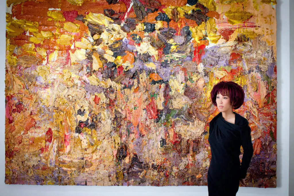 Pearl Lam antaŭ The River Full in Red de artisto Zhu Jinshi (The River Full in Red, 2006, Petrolo sur kanvaso, 290 x 400 cm) Fotokredito: Ĝentileco de Julian de Hauteclocque Howe