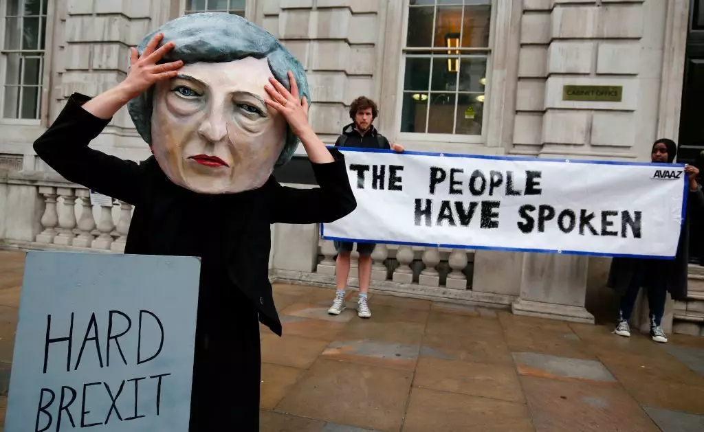 Isang demonstrador ang nagsusuot ng maskara na naglalarawan sa Punong Ministro ng Britain at pinuno ng Conservative Party na si Theresa May sa panahon ng isang photocall sa protesta malapit sa entrance ng 10 Downing Street sa central London noong Hunyo 9, 2017 dahil ang mga resulta mula sa isang snap general election ay nagpapakita na ang Conservatives ay nawalan ng mayorya. Larawan ADRIAN DENNIS/AFP/Getty Images.