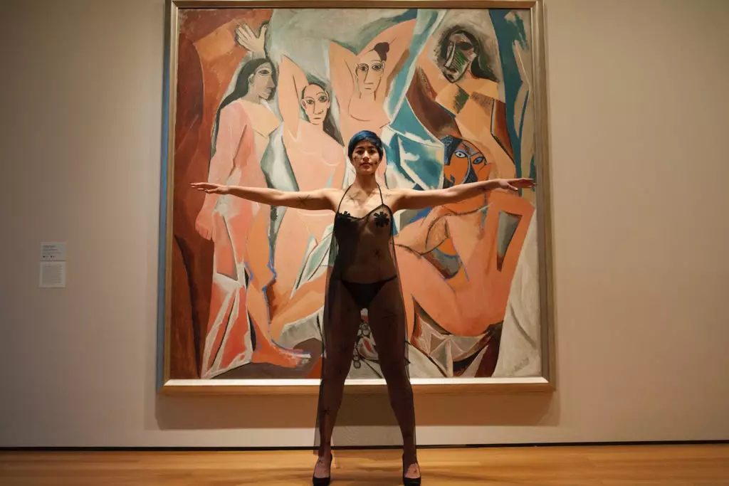 La protestprezento de Emma Sulkowicz, kun Les Demoiselles d'Avignon de Pablo Picasso ĉe la Muzeo de Moderna Arto. Foto ĝentileco de Sangsuk Sylvia Kang.