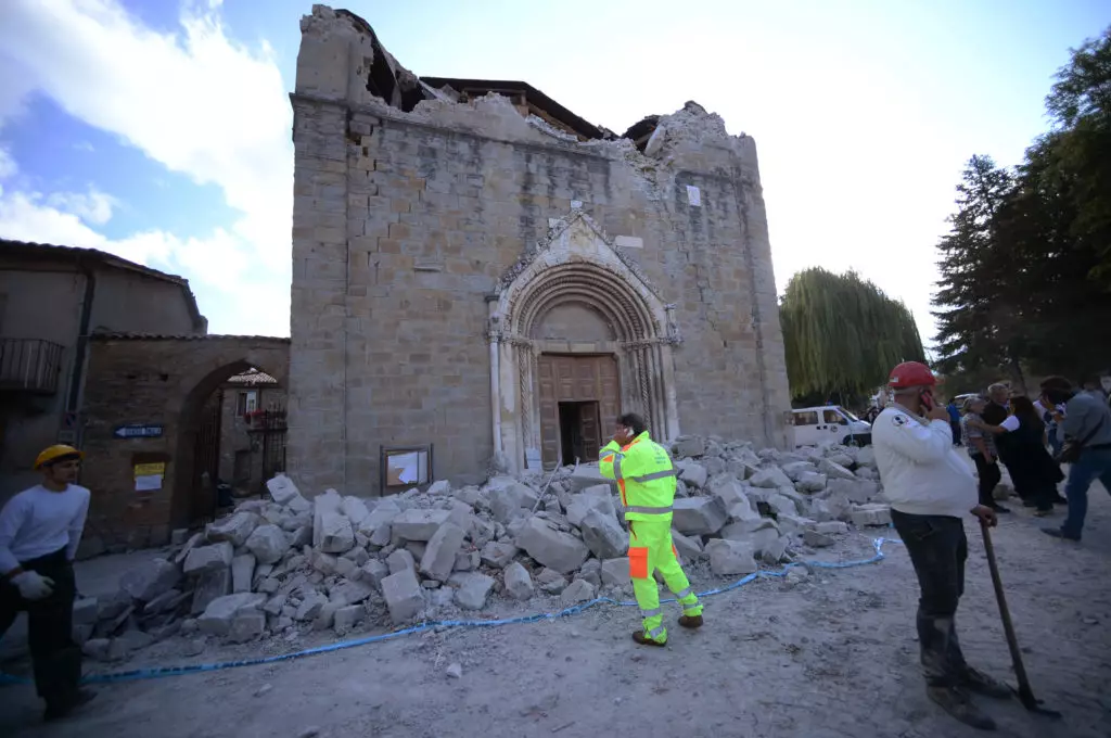 Pessoas ficam em frente a uma igreja danificada em Amatrice em 24 de agosto de 2016. Foto: Filippo Monteforte/AFP/Getty Images.