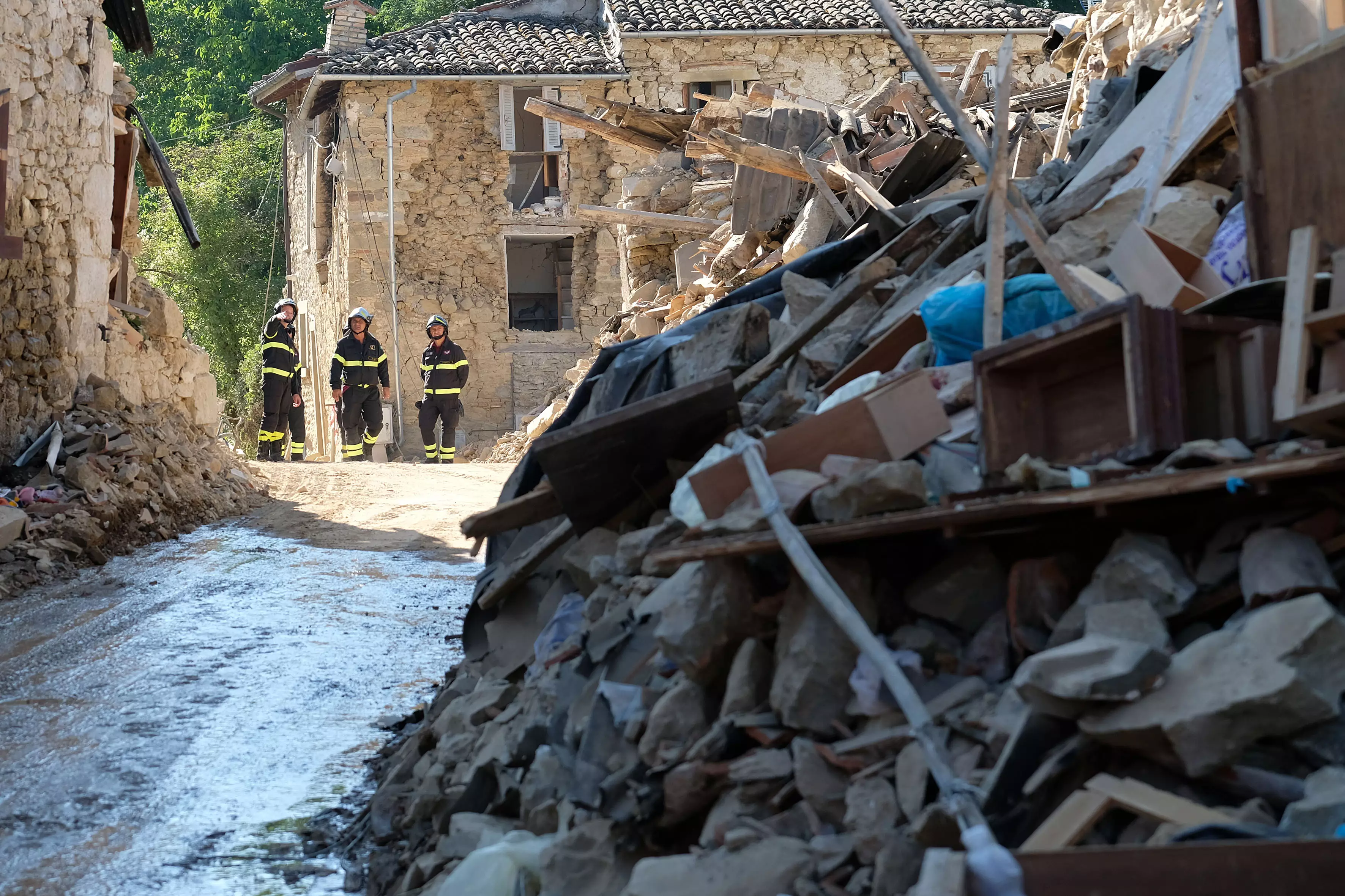 Bombeiros italianos ficam em meio a ruínas durante operação para reabrir a estrada no Rio, uma pequena vila perto de Amatrice. Foto: MARIO LAPORTA/AFP/Getty Images.