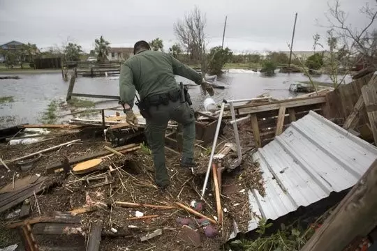 Aġent tal-Għassa tal-Fruntiera tal-Istati Uniti jfittex is-superstiti wara l-Uragan Harvey qrib Rockport, Texas, 27 ta’ Awwissu 2017. Korteżija tan-National Endowment for the Humanities.