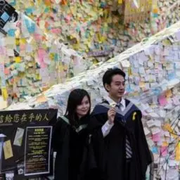 Studenti che indossano abiti da laurea posano per una foto davanti alla pro-democrazia di Hong Kong