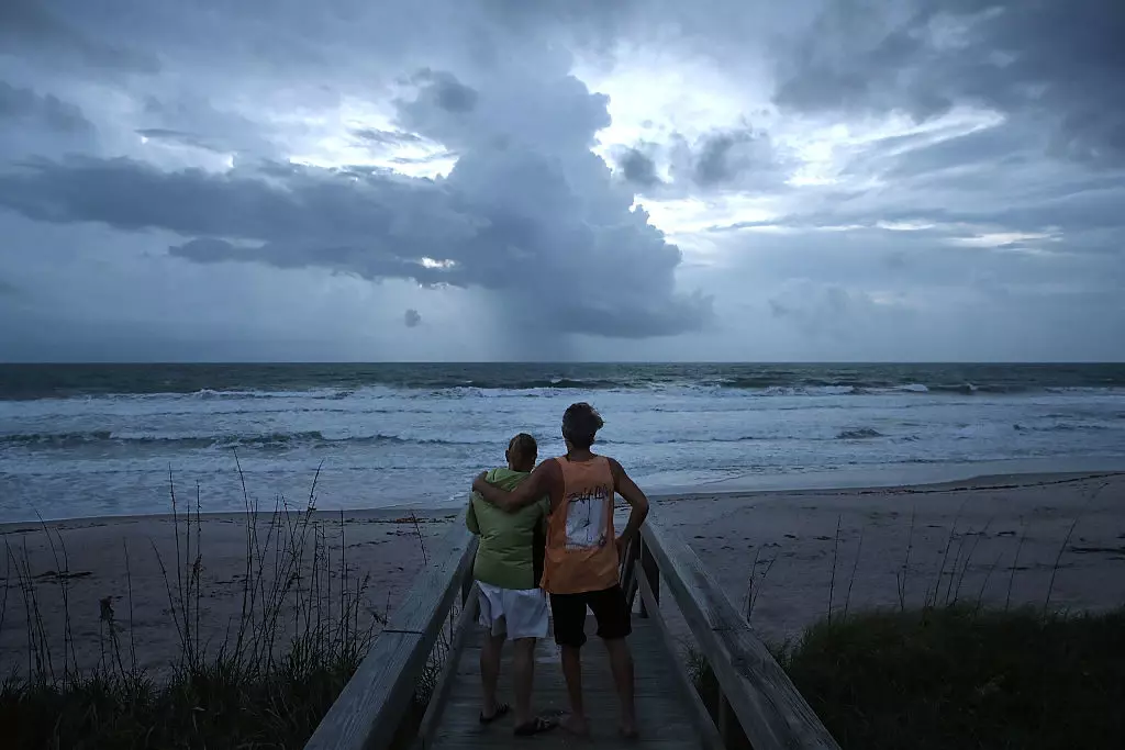 Rod Smith jina xwe Karen hembêz dike dema ku ew di 6ê Cotmeha 2016-an de li ser Satellite Beach, Florida, li surf-ê dihejîne. Tê payîn ku bahoza Matthew îro piştî nîvro bigihêje herêmê. Wêne Mark Wilson / Getty Images.