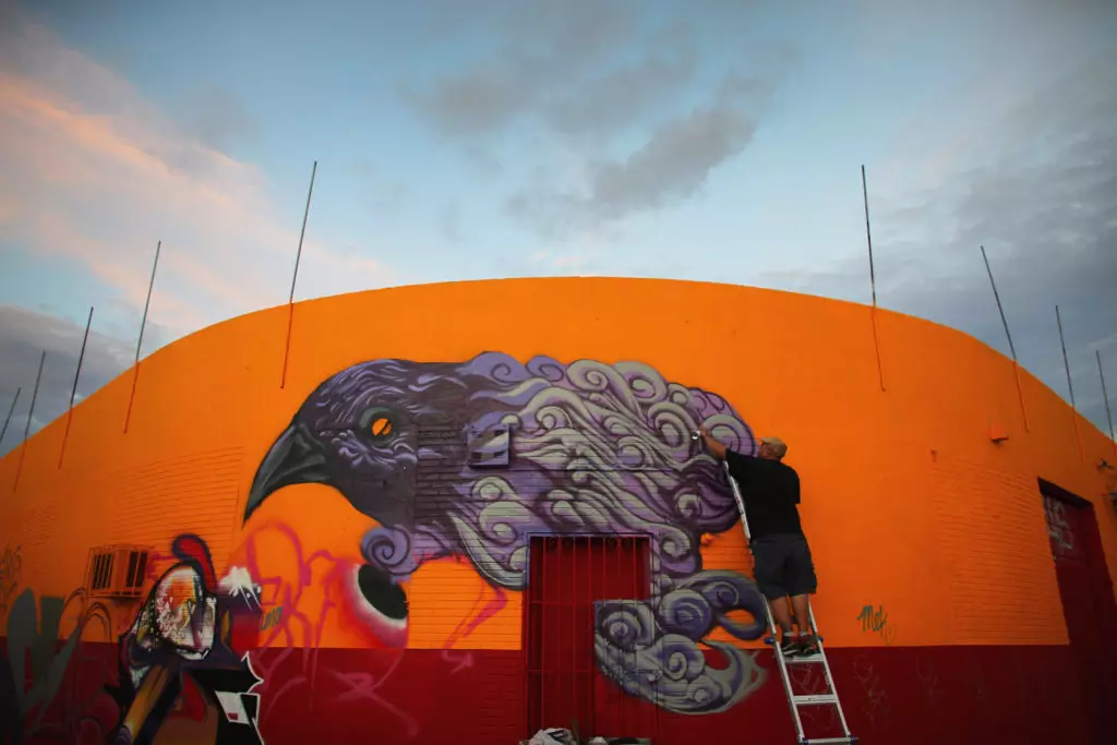 Konstnären känd som Czrprz målar en korp på väggen i en byggnad i Park of Wynwood Walls (2012). Med tillstånd av Getty Images. Foto av Joe Raedle.