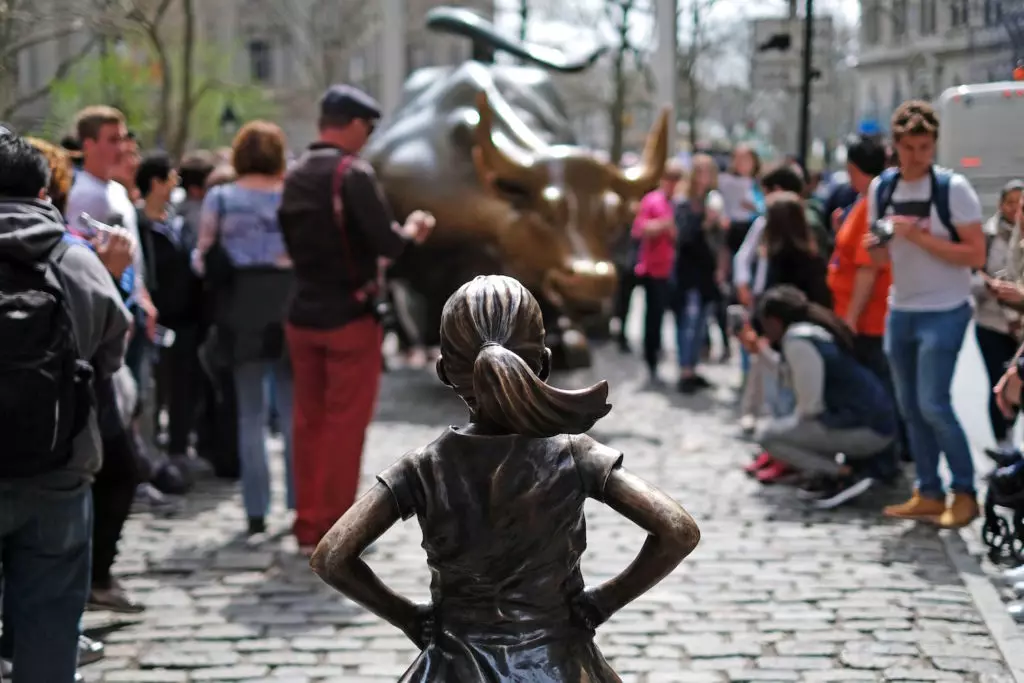 Kristen Visbal Bebaimės mergaitės statula stovi priešais Arturo DiModica ikonišką Charging Bull skulptūrą, kol turistai fotografuojasi. DiModica teigia, kad „Fearless Girl“ pažeidžia jo autorių teises, iškraipo jo meninę žinią ir turėtų būti perkelta kitur. Jewel Samad / AFP / Getty Images sutikimu.