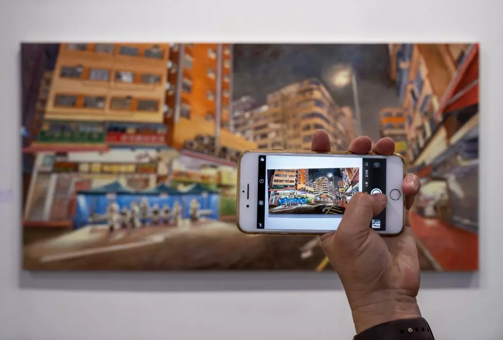 Een bezoeker maakt een foto van een schilderij op Art Basel Hong Kong in mei 2021. (Foto door Miguel Candela/SOPA Images/LightRocket via Getty Images)