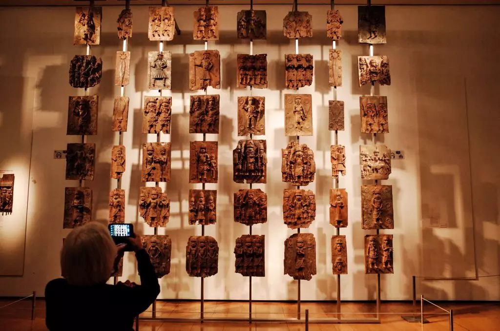 Un visitatore scatta foto dei controversi bronzi del Benin che sono in mostra al British Museum di Londra. Foto: David Cliff/SOPA Images/LightRocket via Getty Images.