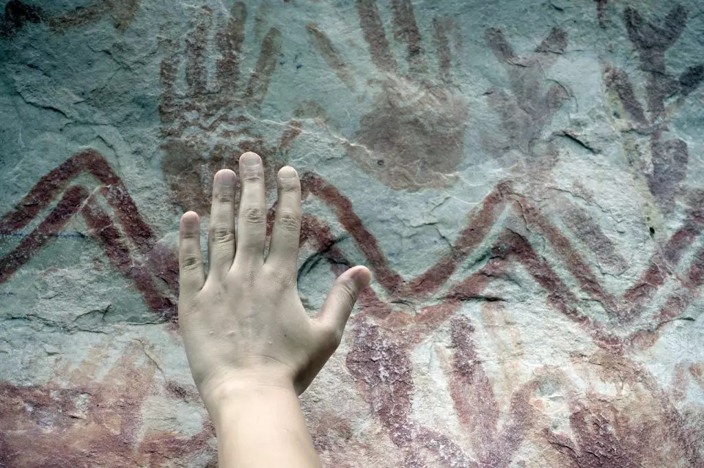 Paleoantropologinja Ella Al-Shamahi upoređuje svoju ruku s otiskom šake nastalom prije oko 12.000 godina u Cerro Azulu u državi Guaviare, Kolumbija. Fotografija Marie-Claire Thomas, ljubaznošću Wild Blue Media.