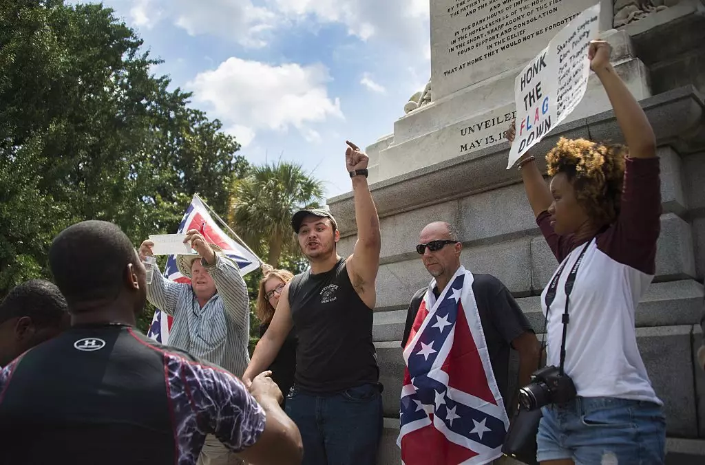 Bannaanbaxayaasha calanka u janjeedha Peter Manos (dhexda) ayaa ku doodaya mudaaharaad ka soo horjeeda calanka Confederate Jalaudin Abdul-Hamib (bidix) bannaanka Aqalka Gobolka South Carolina ee Columbia, South Carolina, Juun 27, 2015. Sawirka Jim Watson/AFP/Getty Images.