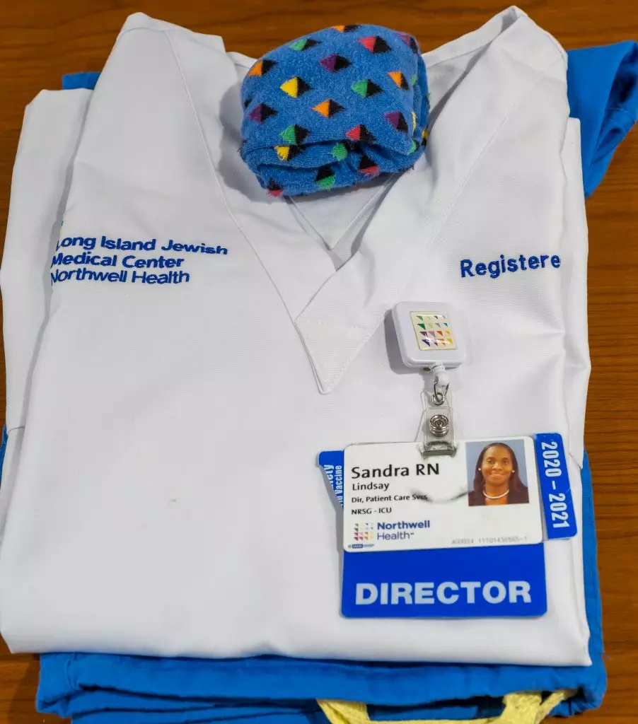 Scrubs u badge tal-ID tal-Persunal li tappartjeni lil Sandra Lindsay, infermiera tal-ICU f'Long Island Jewish Medical Center fi New York, li kienet l-ewwel persuna magħrufa li rċeviet il-vaċċin fl-Istati Uniti. Ritratt bil-kortesija ta' Northwell Health.