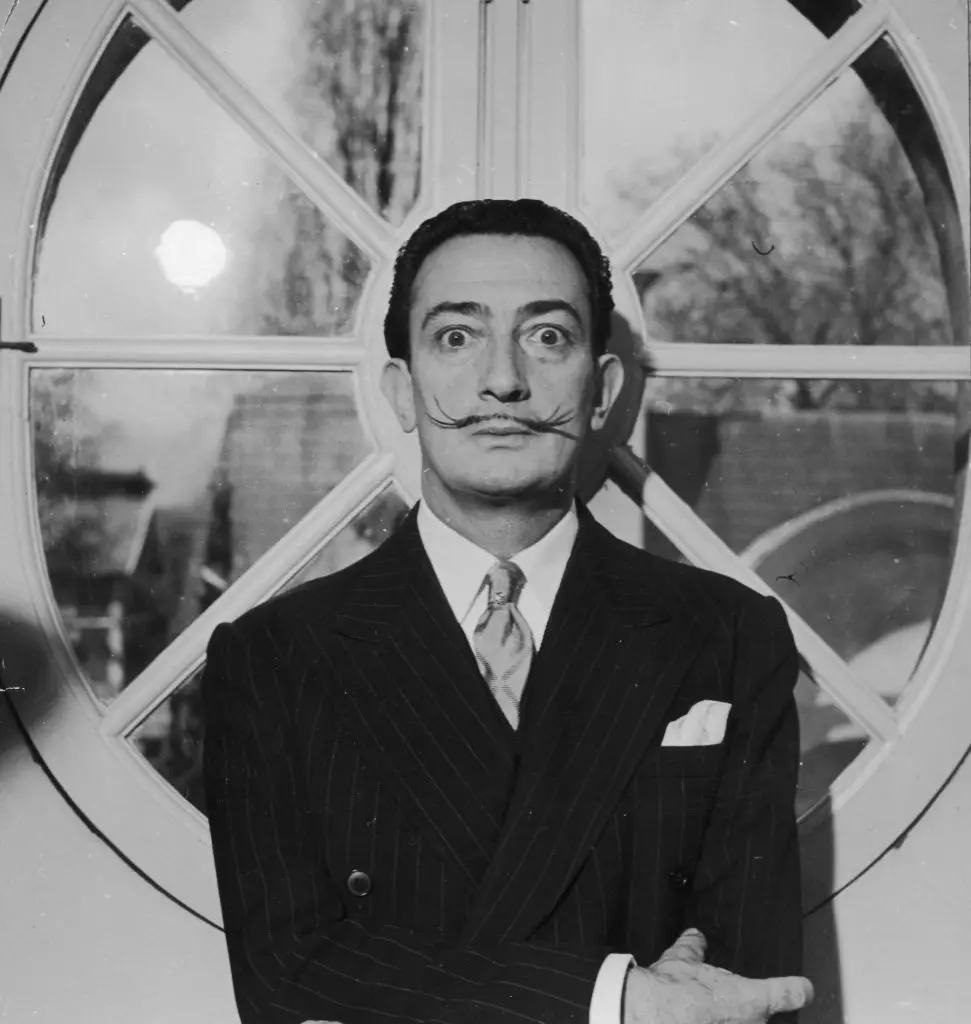 Spanish Surrealist artist Salvador Dali (1904–1989). He is wearing a pinstriped suit and his trademark mustache. Photograph by Hulton Archive/Getty Images.