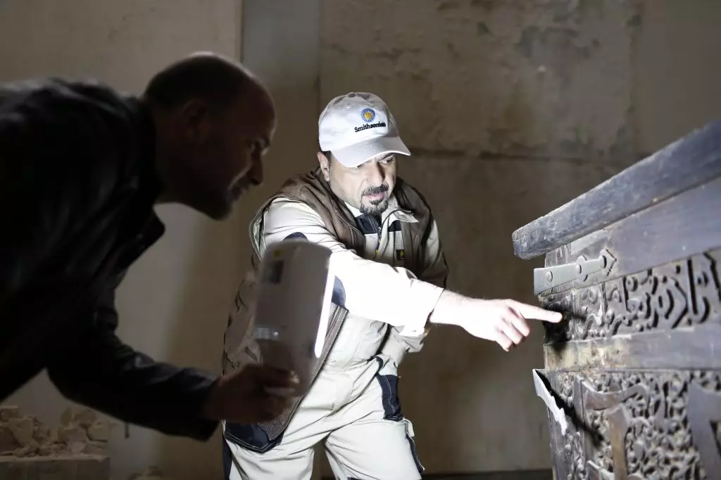 Arkeolog dan direktur Museum Budaya Mosul Zaid Ghazi Saadallah dan kepala konservasi museum, Saad Ahmed (memegang senter), memeriksa cenotaph kayu di Islamic Hall Museum Budaya Mosul pada Februari 2019. Foto oleh Sebastian Meyer.