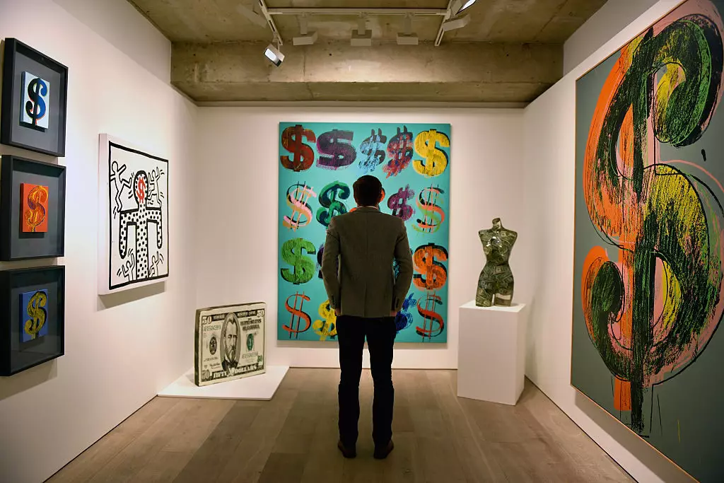 Un visiteur étudie Dollar Signs (1981) d'Andy Warhol pour "The Art of Making Money" chez Sotheby's le 8 juin 2015 à Londres. Photo publiée avec l'aimable autorisation de Mary Turner/Getty Images.