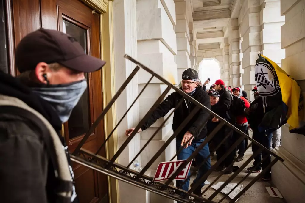 Un miembro de una mafia pro-Trump golpea la entrada del edificio del Capitolio en un intento de obtener acceso el 6 de enero de 2021 en Washington, DC. Una turba pro-Trump irrumpió en el Capitolio, rompió ventanas y se enfrentó a agentes de policía. Los partidarios de Trump se reunieron hoy en la capital de la nación para protestar por la ratificación de la victoria del Colegio Electoral del presidente electo Joe Biden sobre el presidente Trump en las elecciones de 2020. Foto de Jon Cherry/Getty Images.