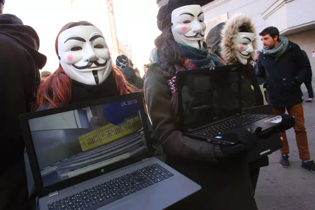 Gníomhaithe ag caitheamh maisc Guy Fawkes, ar fearr leis an líonra hacker iomráiteach ar a dtugtar Anonymous, le linn léirsiú i Maidrid, an Spáinn. (Grianghraf le Mario Roldan/SOPA Images/LightRocket trí Getty Images)