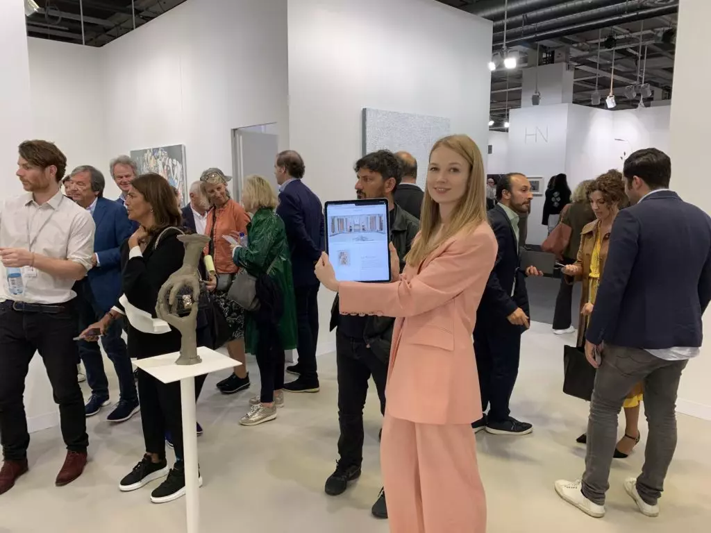 David Zwirner Mkurugenzi wa Mauzo Mtandaoni Elena Soboleva akiwa na iPad yake kwenye kibanda cha sanaa cha Art Basel mnamo 2019. Picha na Andrew Goldstein.